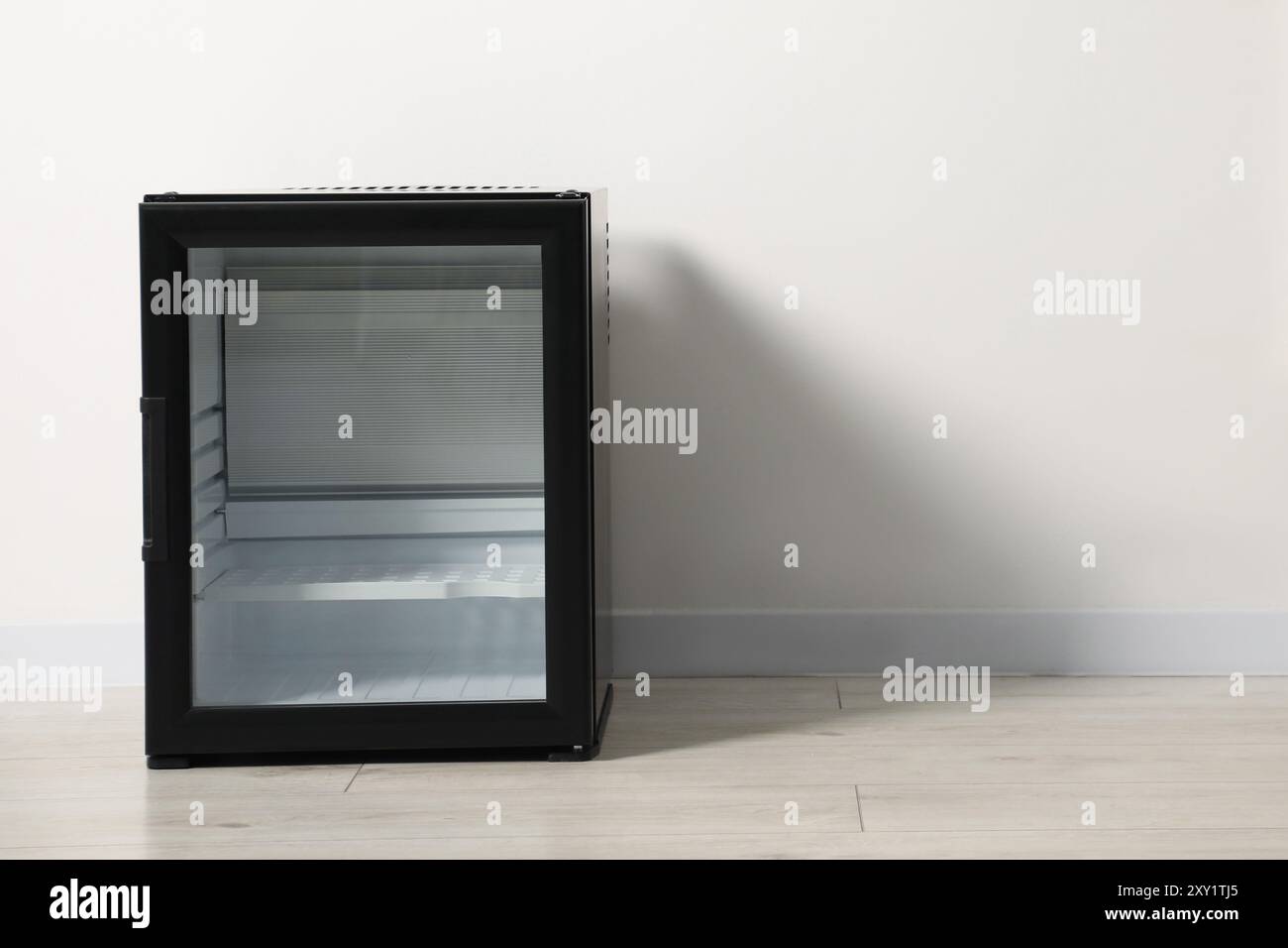 Empty modern mini refrigerator near white wall, space for text Stock ...