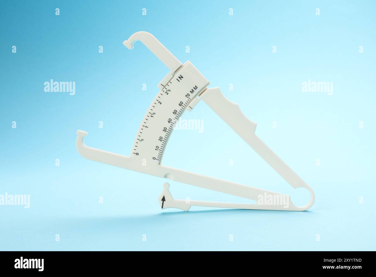 Plastic body fat caliper on light blue background Stock Photo - Alamy