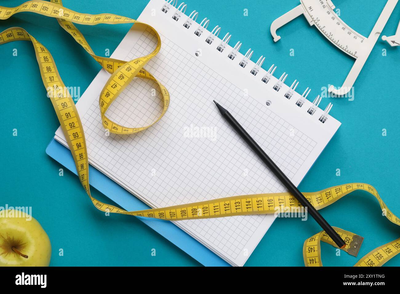 Flat lay composition with body fat caliper, measuring tape and notebook ...