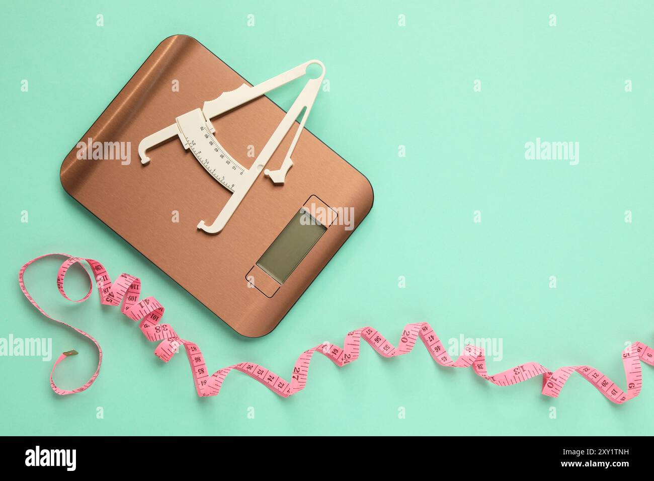 Body fat caliper, measuring tape and kitchen scale on turquoise ...