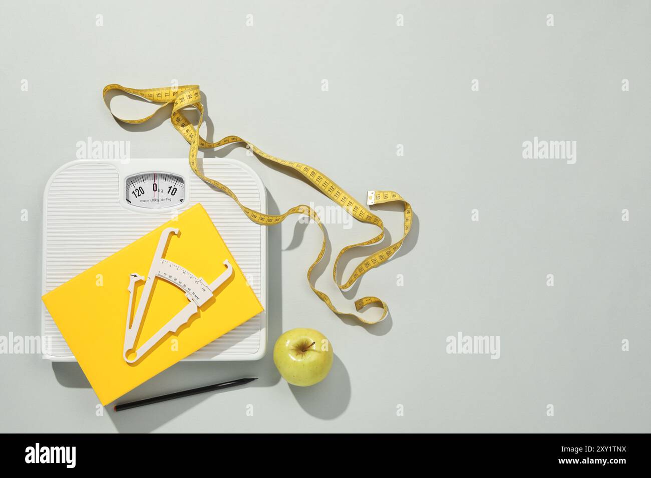 Body fat caliper, measuring tape, scale and notebook on light grey ...