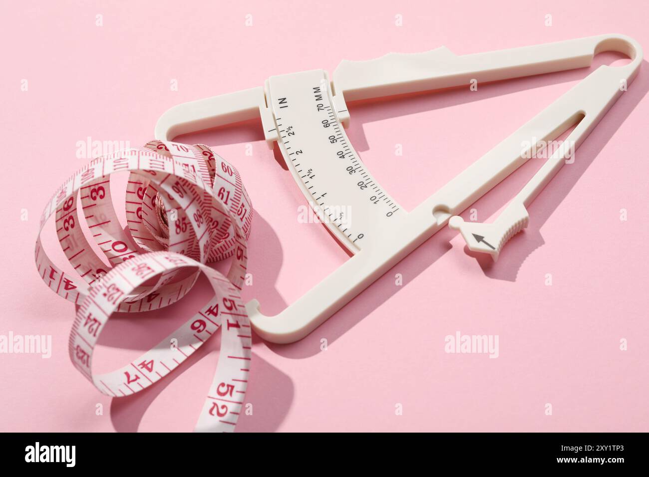 Body fat caliper and measuring tape on pink background, closeup Stock ...