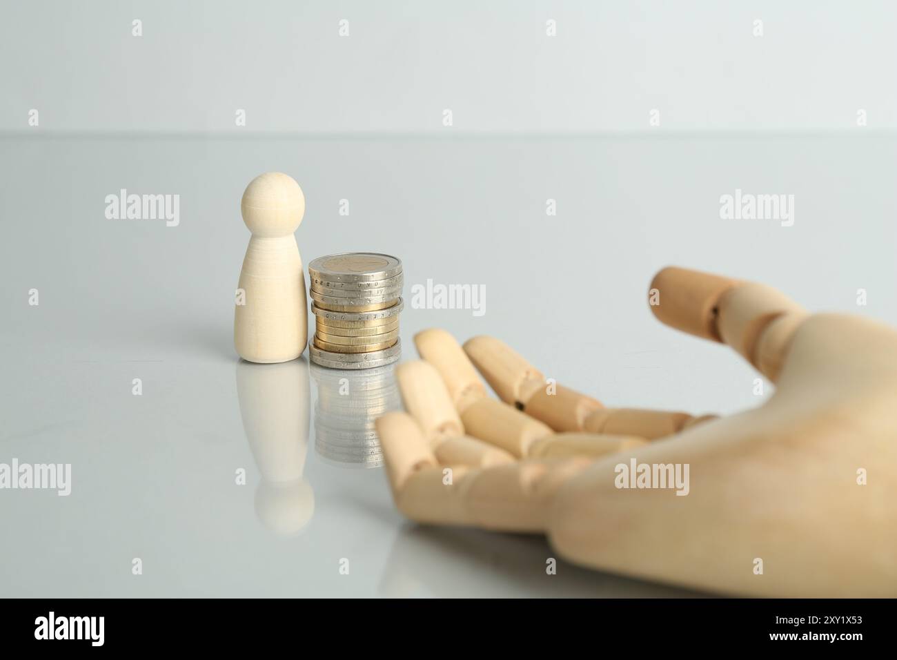 Financial inequality. Human figure, coins and wooden hand on light ...