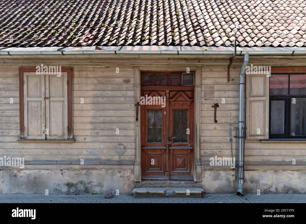 The exterior of an aging wooden house features intricate double doors ...