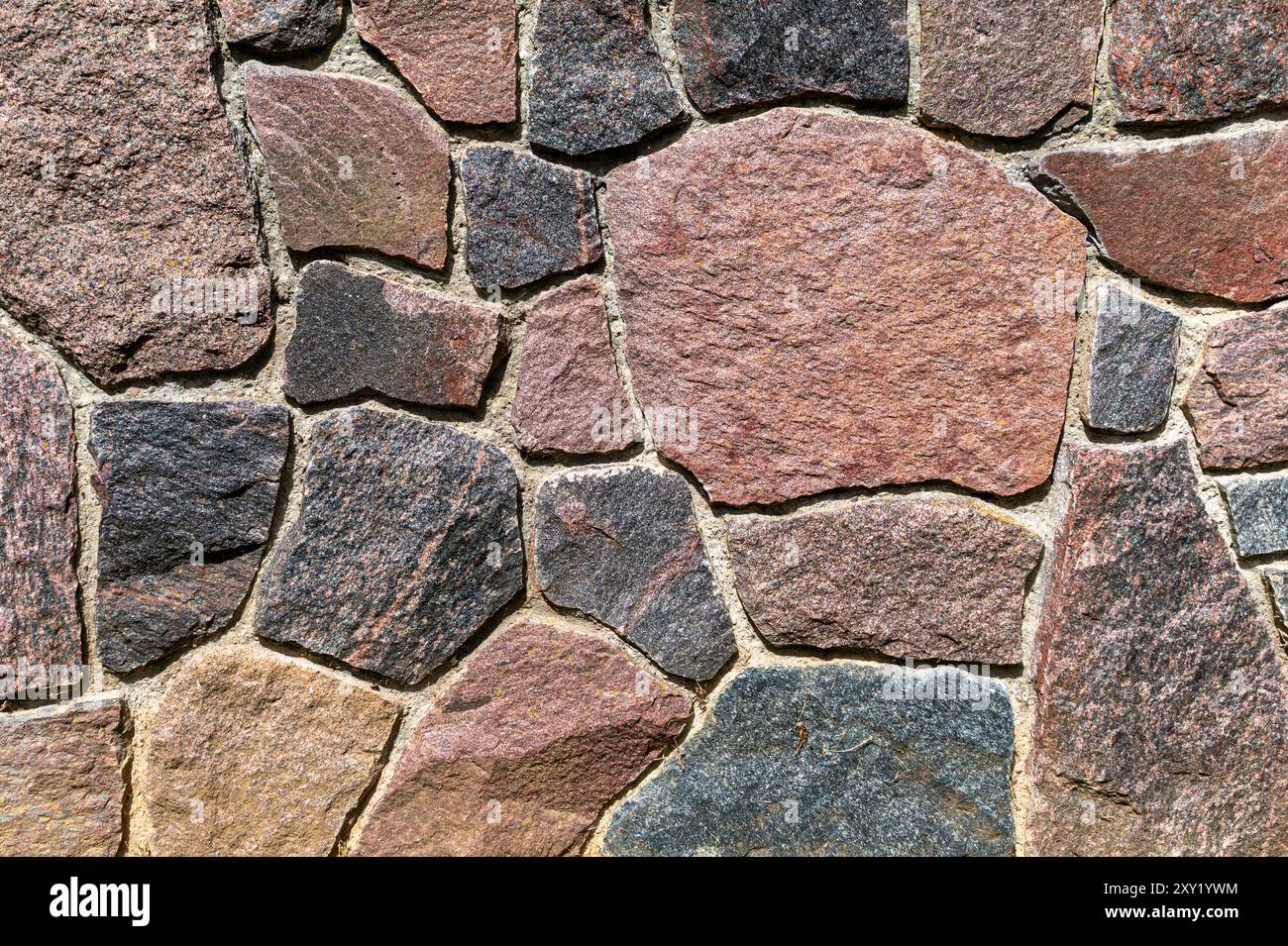 A rustic stone wall features various shapes and tones of natural stones ...