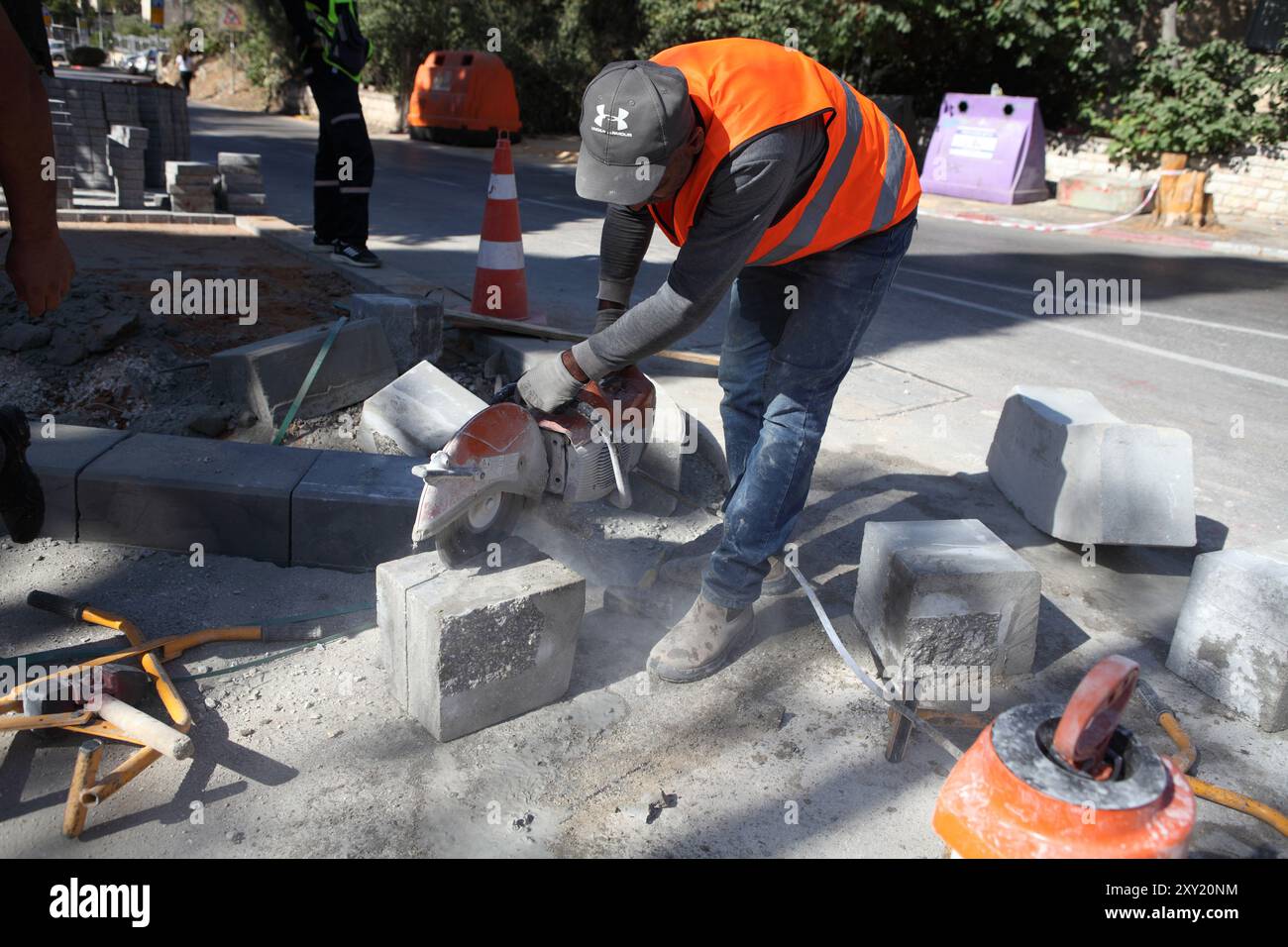 Dust created by a Palestinian worker with protective vest sawing a ...