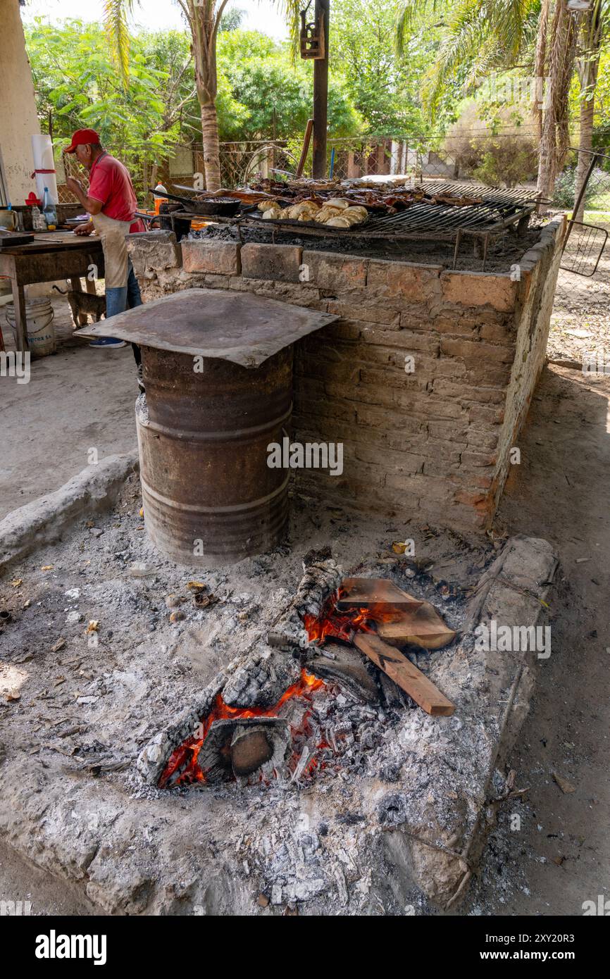 A cook grills meat over coals in a traditional parrilla in Termas de ...
