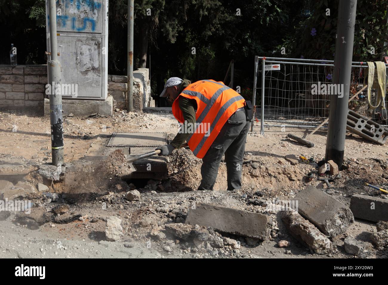 Palestinian Arab foreign worker wearing protective vest uses a shovel ...