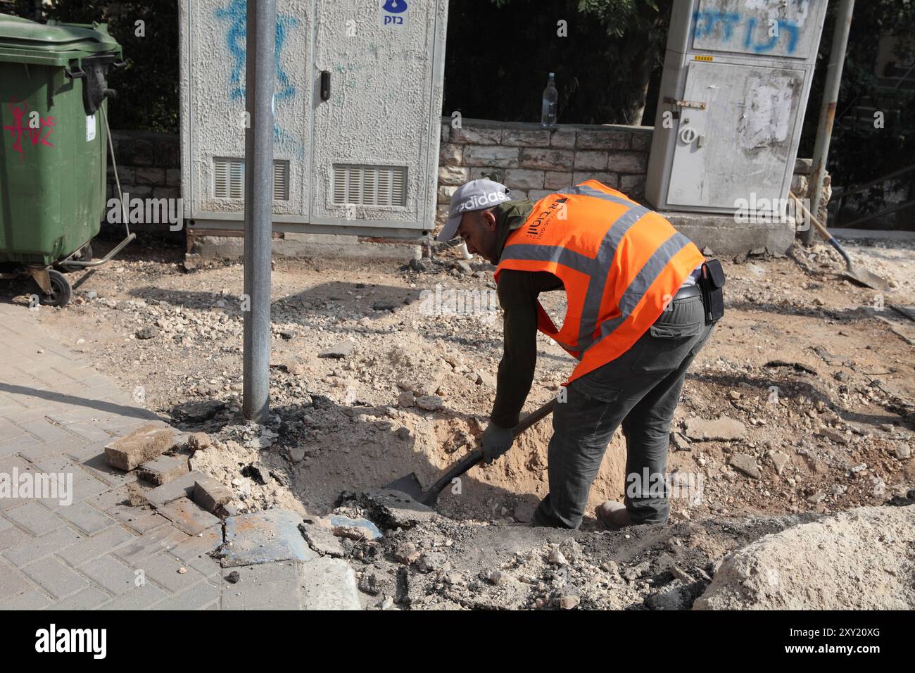 Palestinian Arab foreign worker wearing protective vest uses a shovel ...