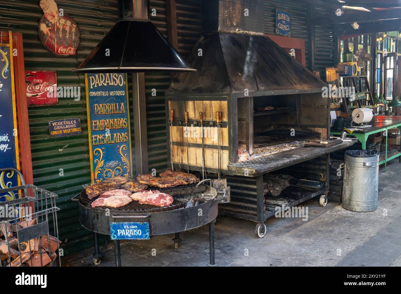 Meat cooking over coals in a wood-fired grill in the outdoor kitchen of ...
