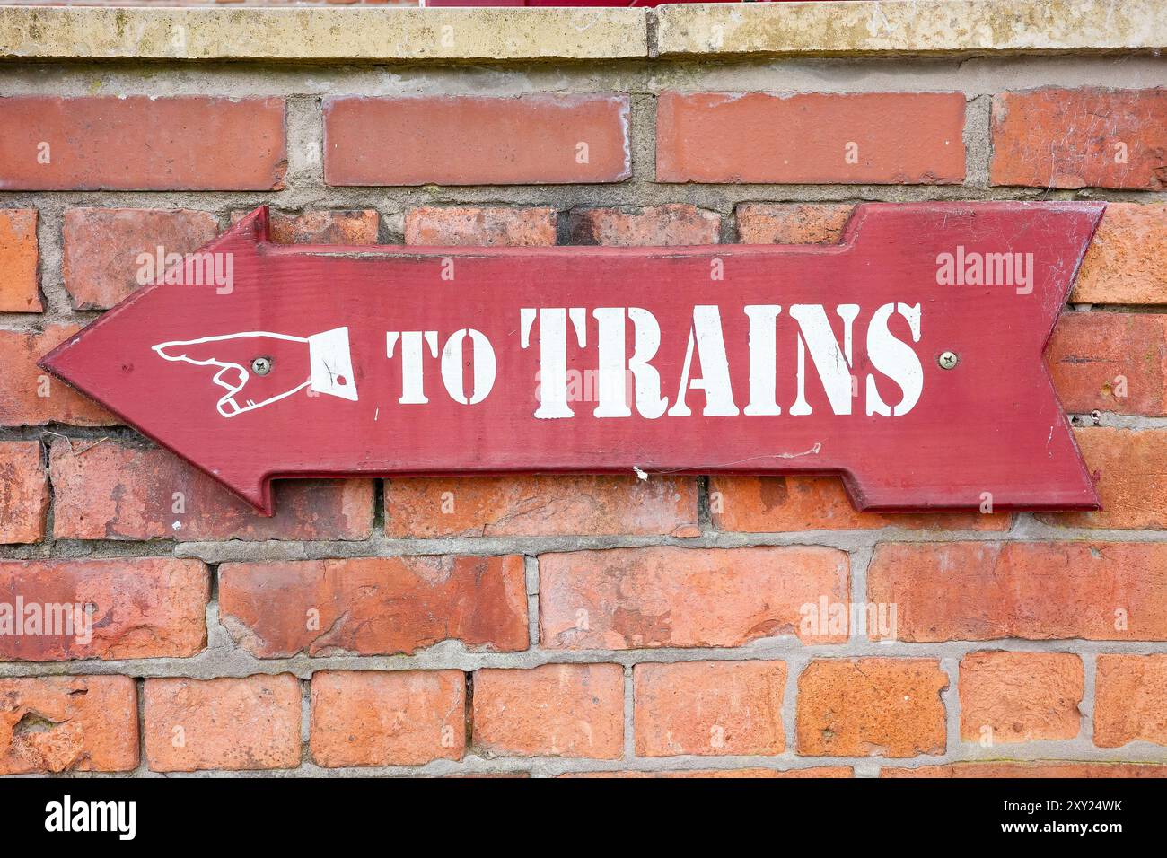 Vintage red arrow sign on brick wall pointing towards the train station ...