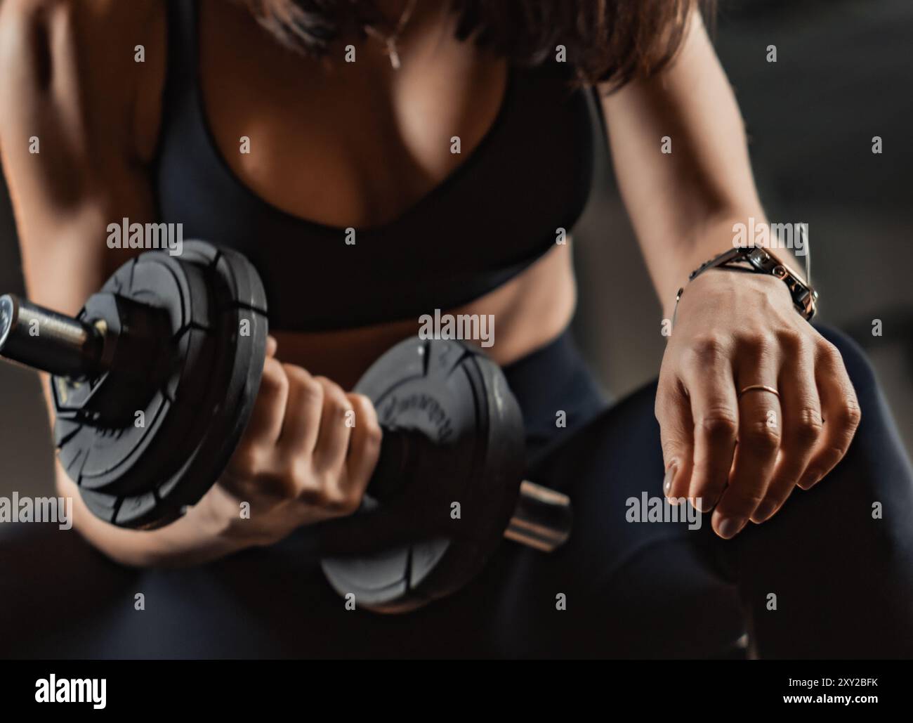 A dedicated female fitness enthusiast lifts a dumbbell in the gym ...