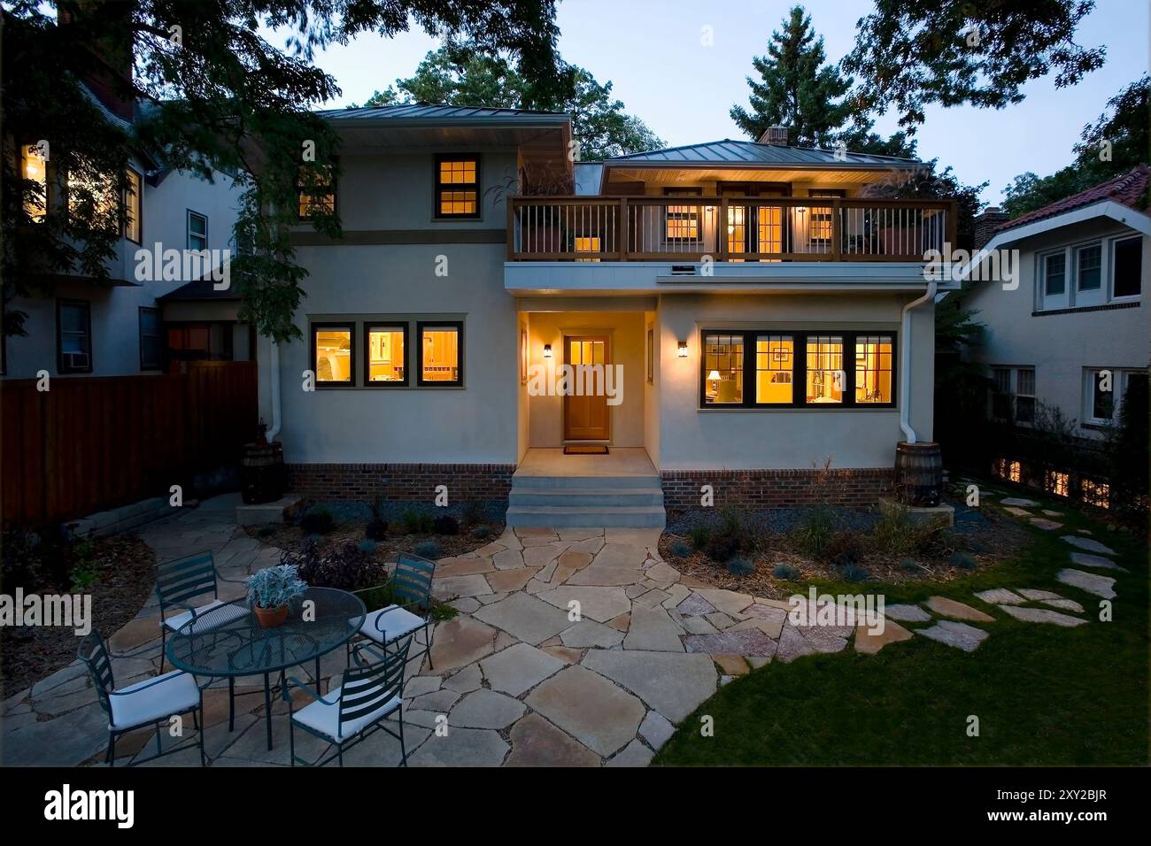 Back of two story stucco house with metal roof and stone patio Stock ...