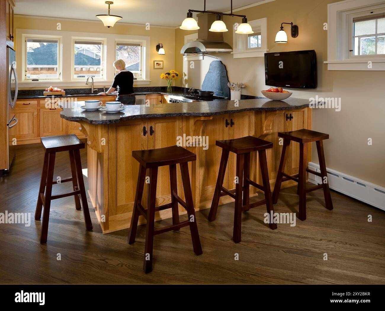 Woman standing at kitchen counter with irregularly shaped granite ...