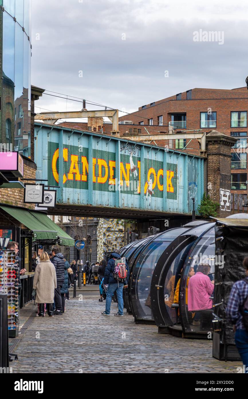 People drinking and eating in dining pods inside the Camden market with ...