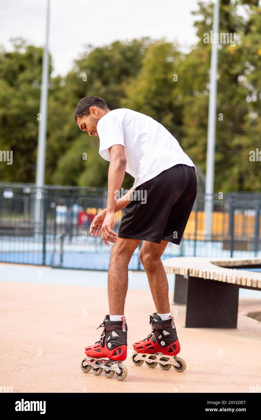 Young man on rollers trying to keep balance and starting to fall down ...