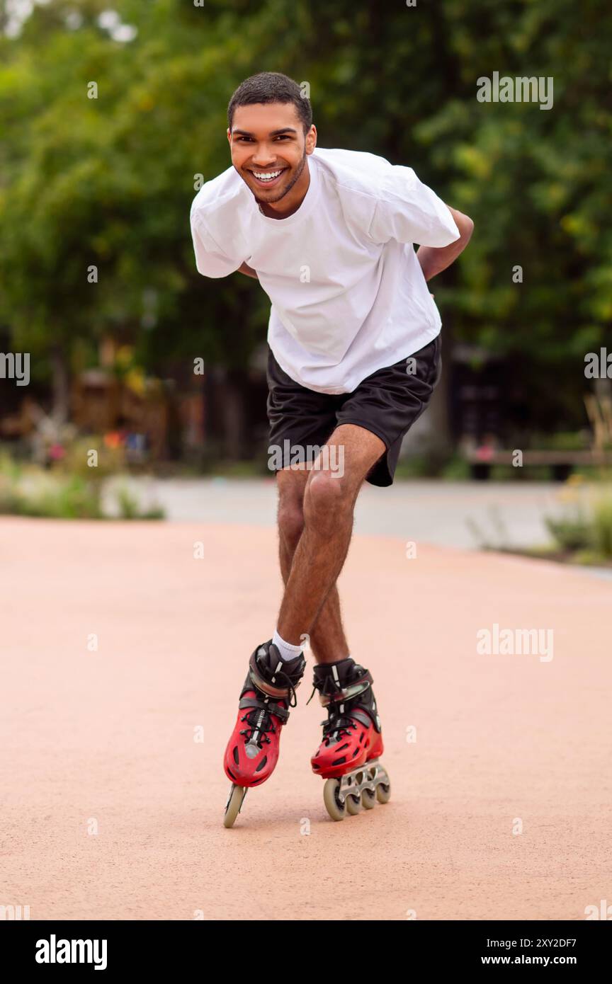 Tall dark-haired young man on rollers in the park having a ride Stock ...