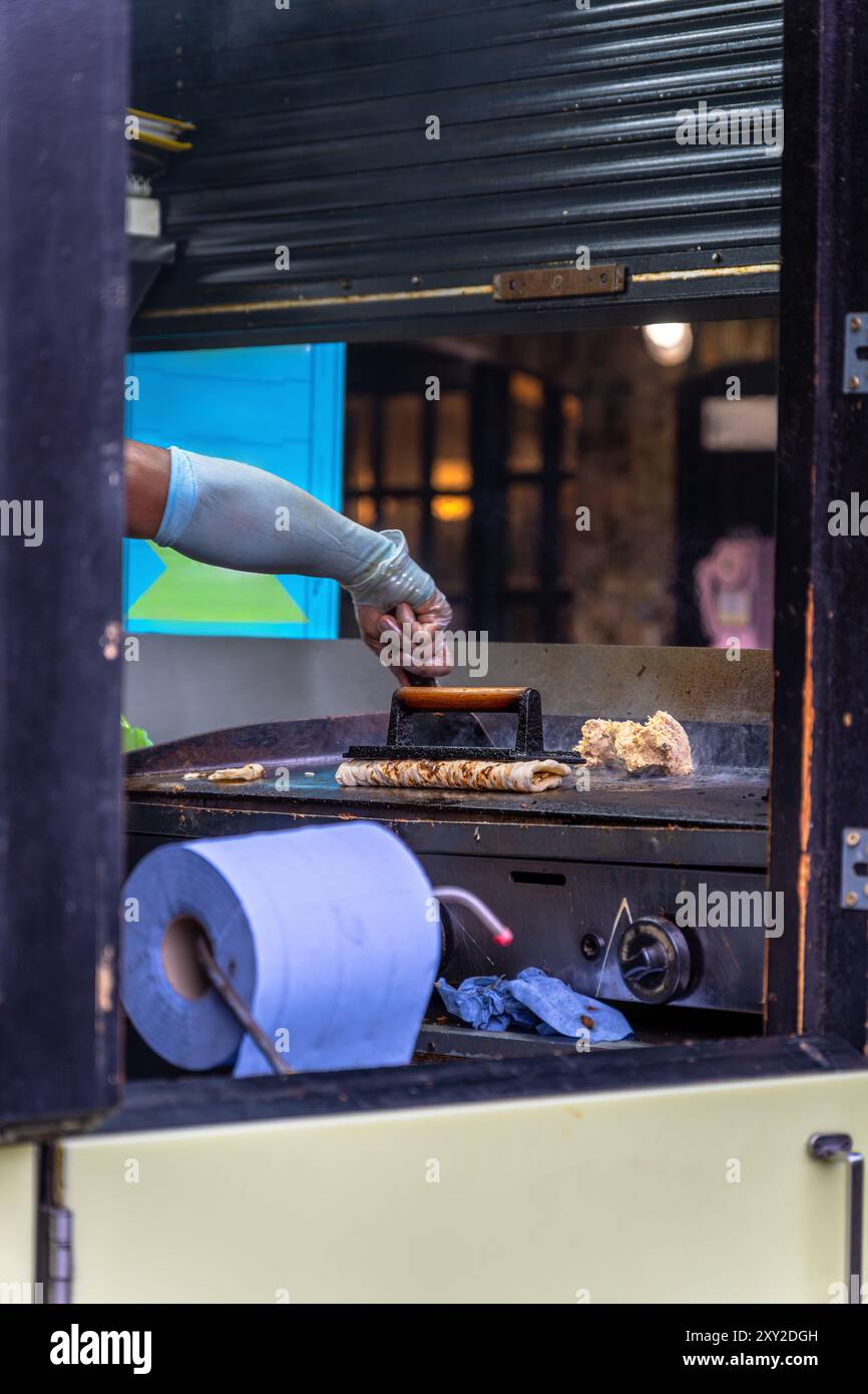 Detail of arm and hand of racialized man with rubber gloves cooking ...