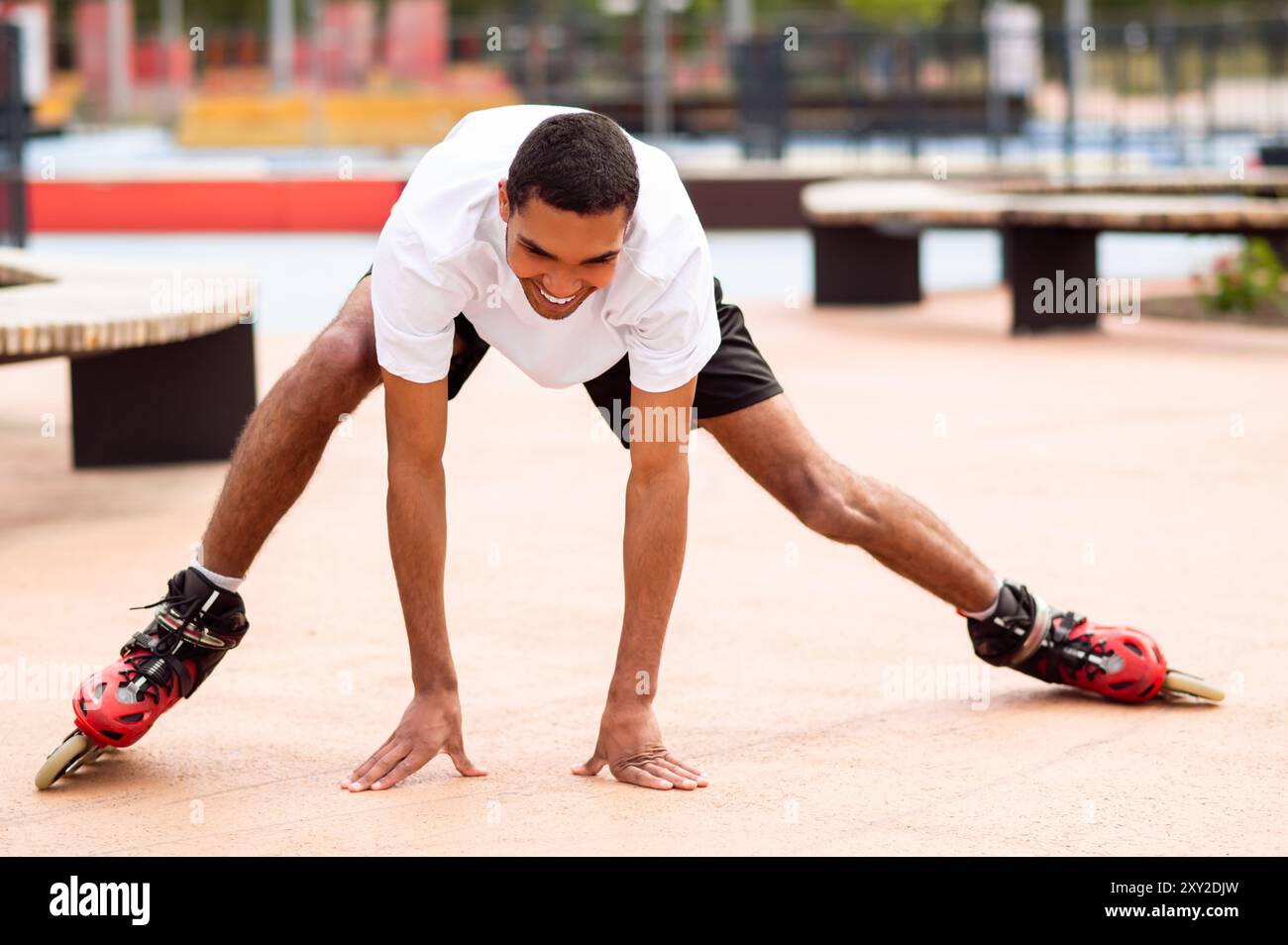 Young man on rollers trying to keep balance and starting to fall down ...