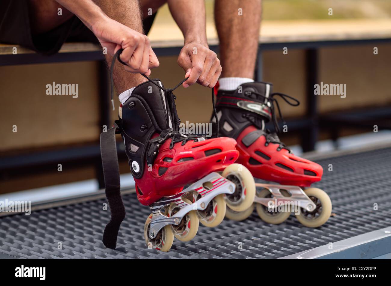 Young man putting on red rollers before the ride Stock Photo - Alamy