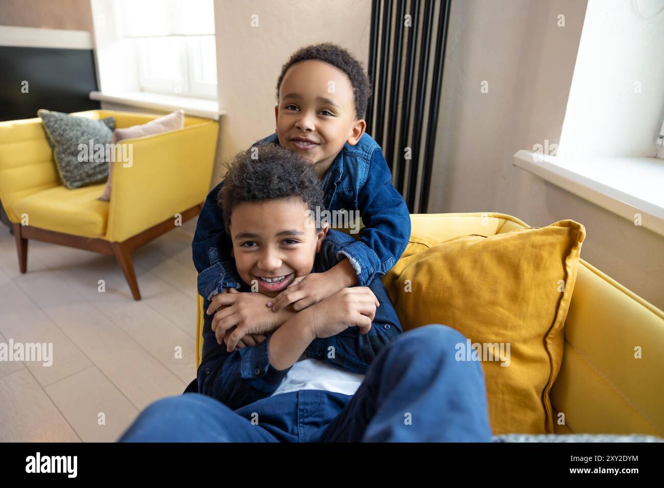 Cheerful brothers siblings having fun hugging while playing on sofa ...