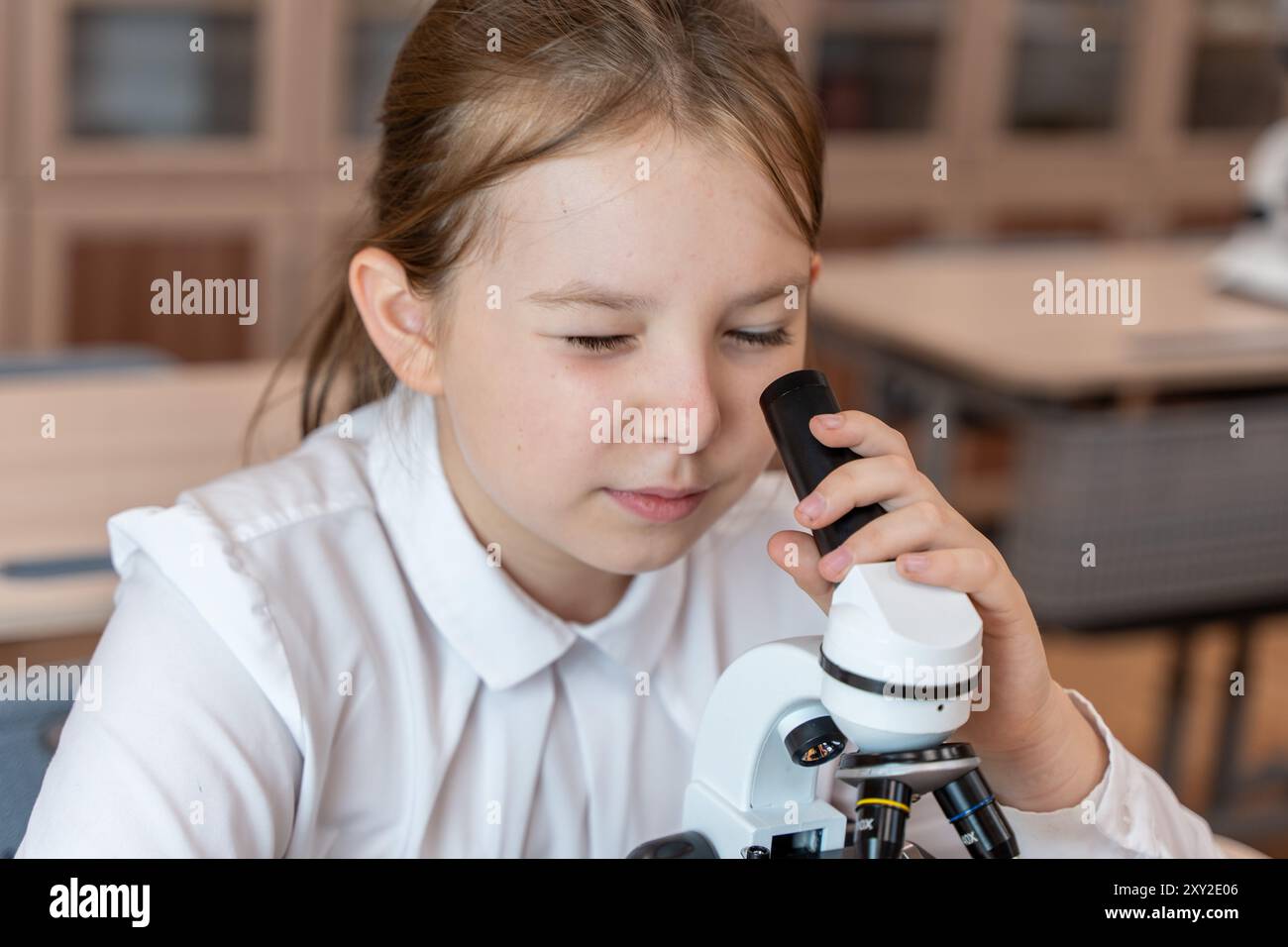 A scientist looks through a microscope in a classroom hi-res stock photography and images - Alamy