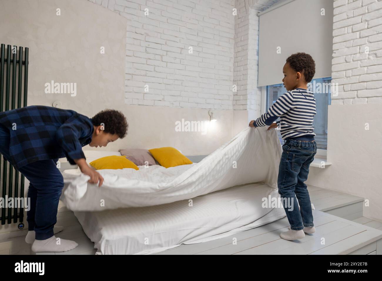 Siblings making bed together and fixing a flock bed Stock Photo - Alamy