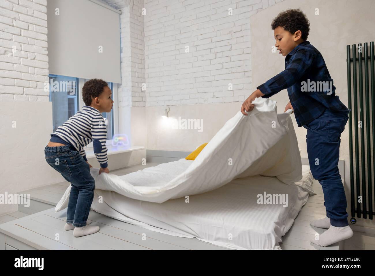 Siblings making bed together and fixing a flock bed Stock Photo - Alamy