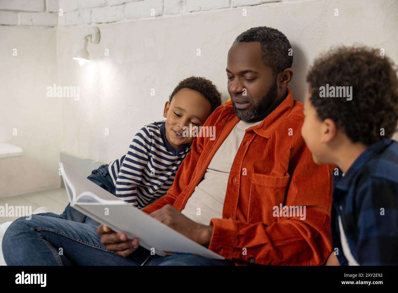 Father and kids reading stories before sleep and looking interested ...