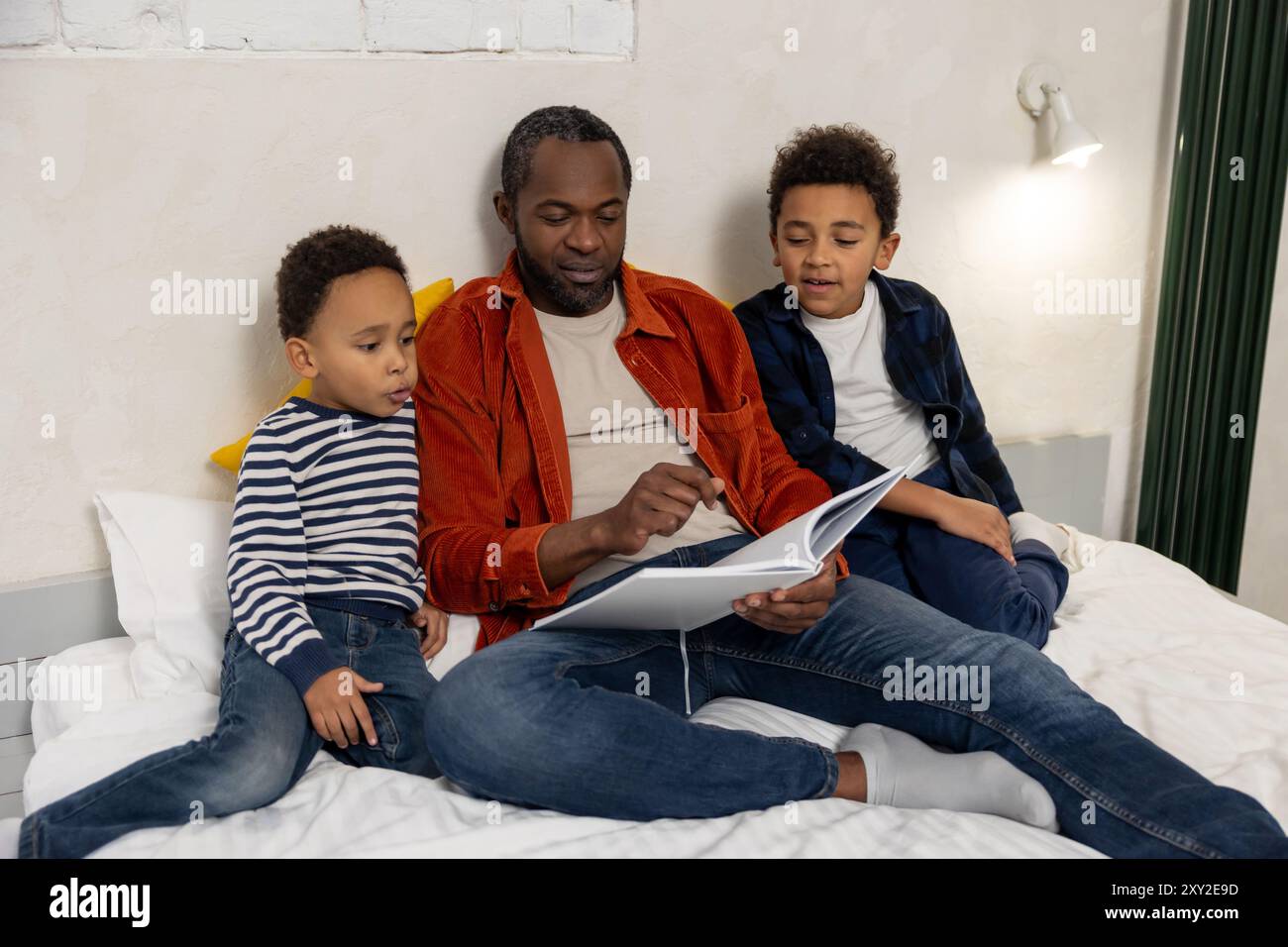 Father and kids reading stories before sleep and looking interested ...