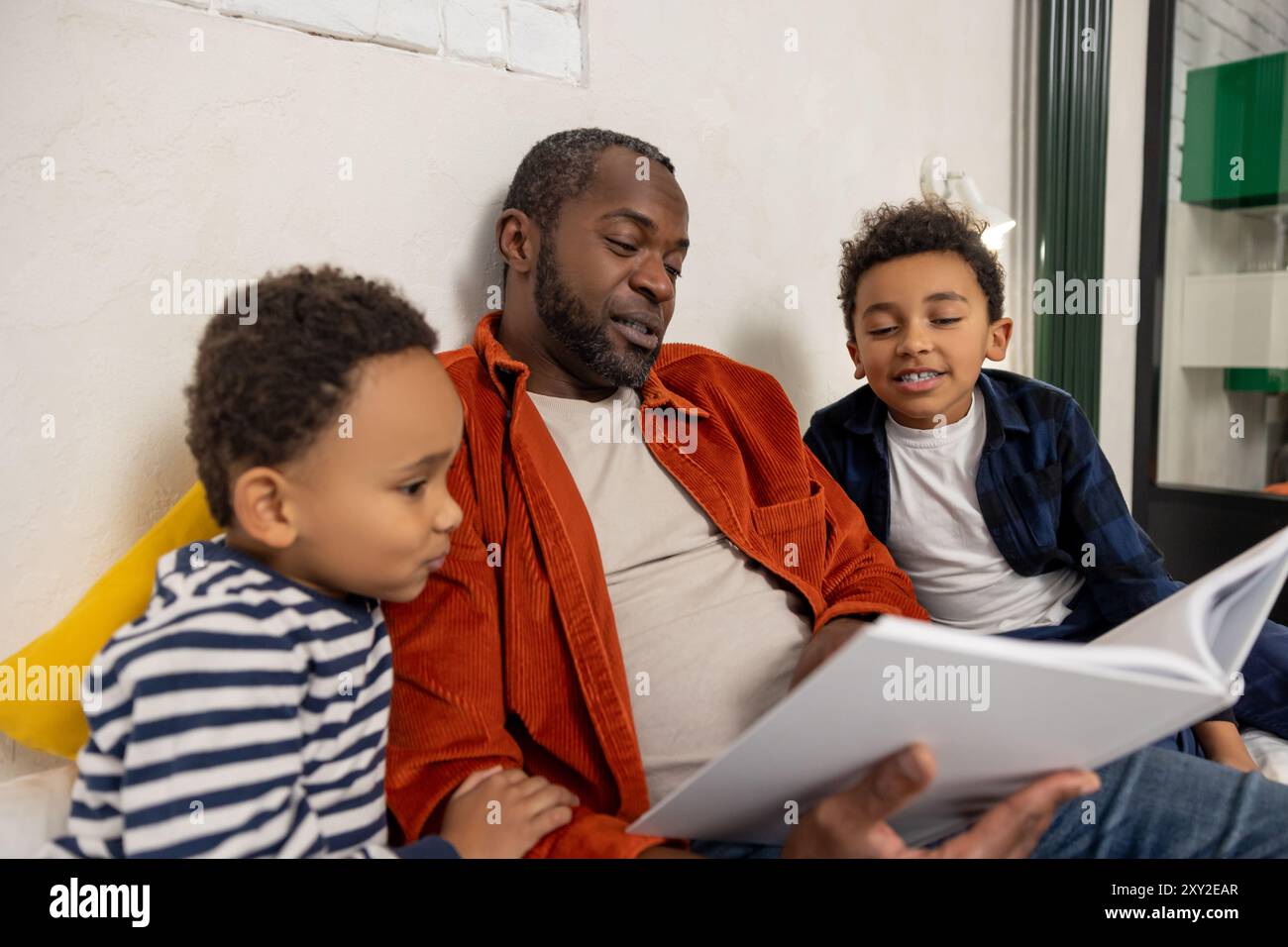 Father and kids reading stories before sleep and looking interested ...