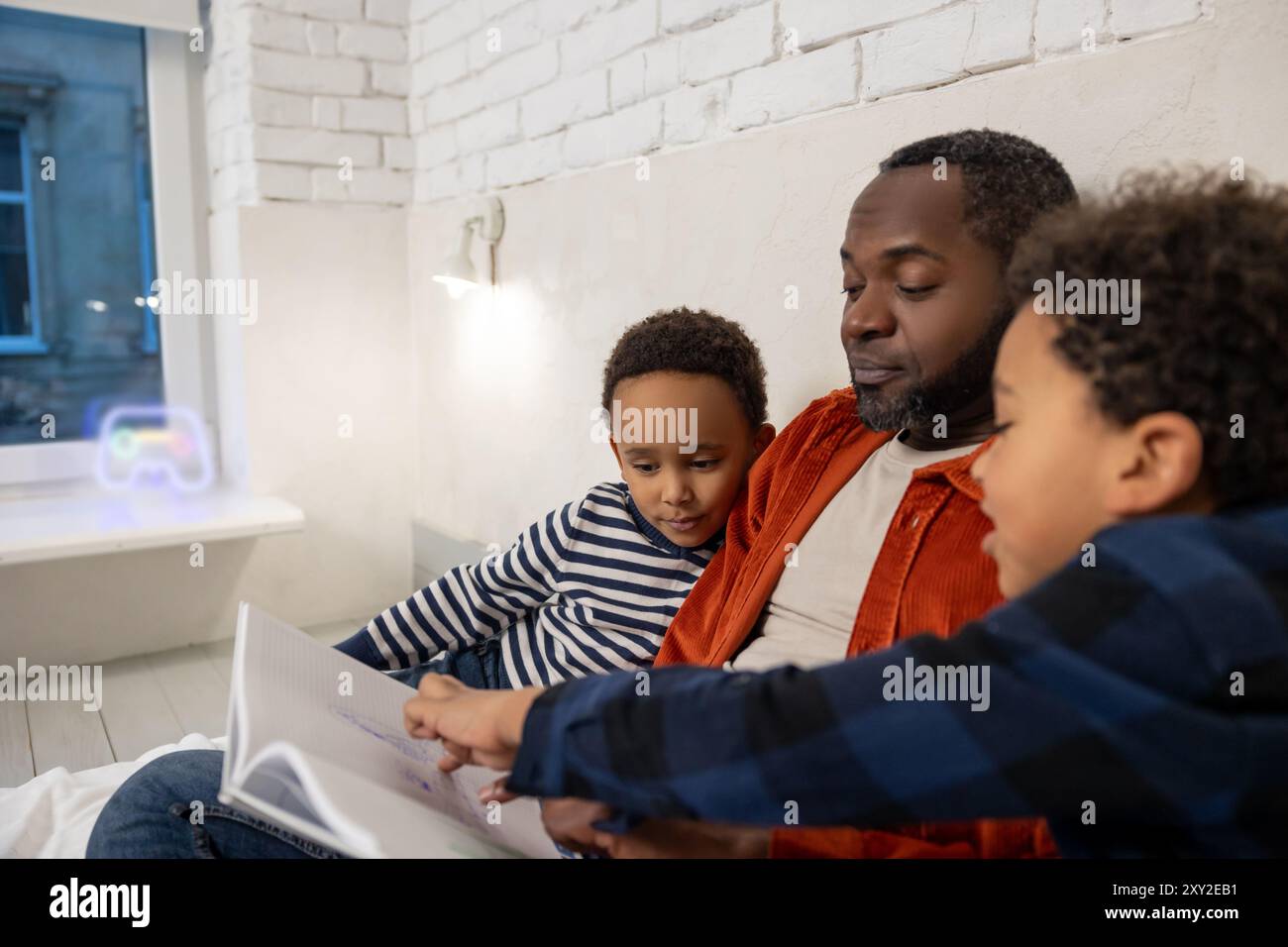 Father and kids reading stories before sleep and looking interested ...