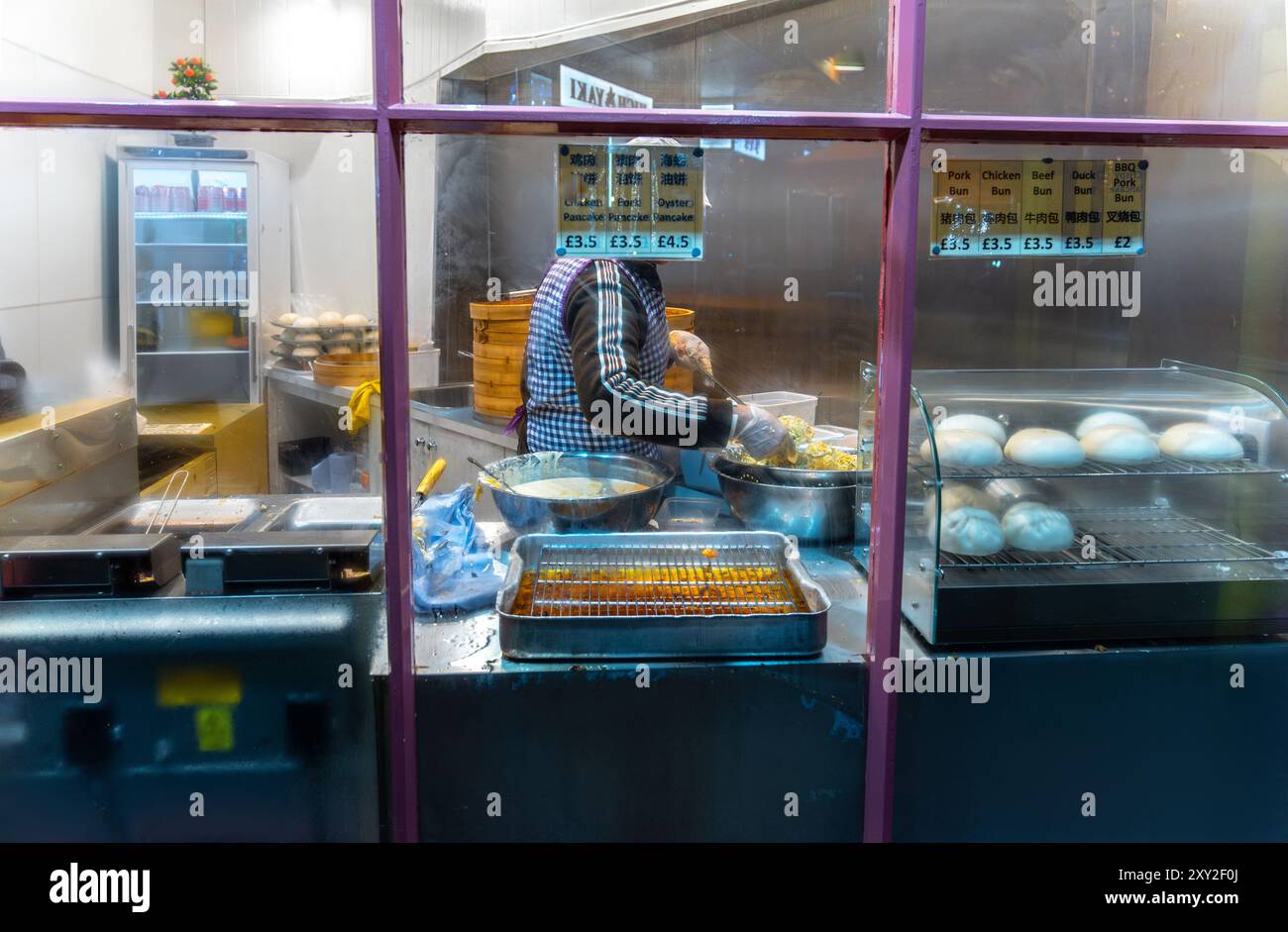 Chinese chef in apron and plastic gloves cooking dough and ingredients ...