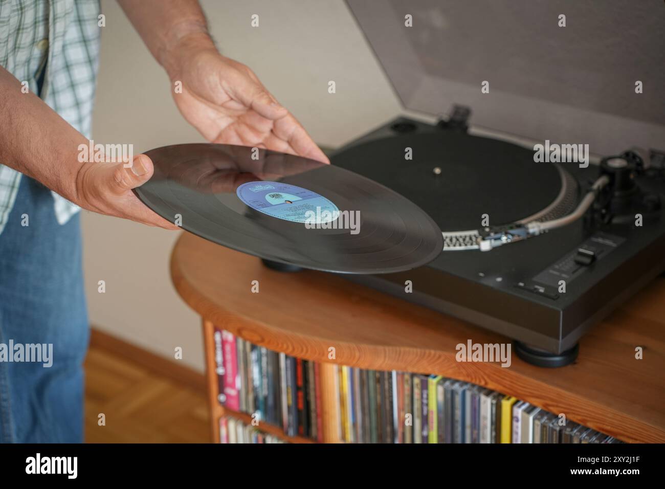 Germany. August 24, 2024. Human hand puts record on a retro vinyl ...