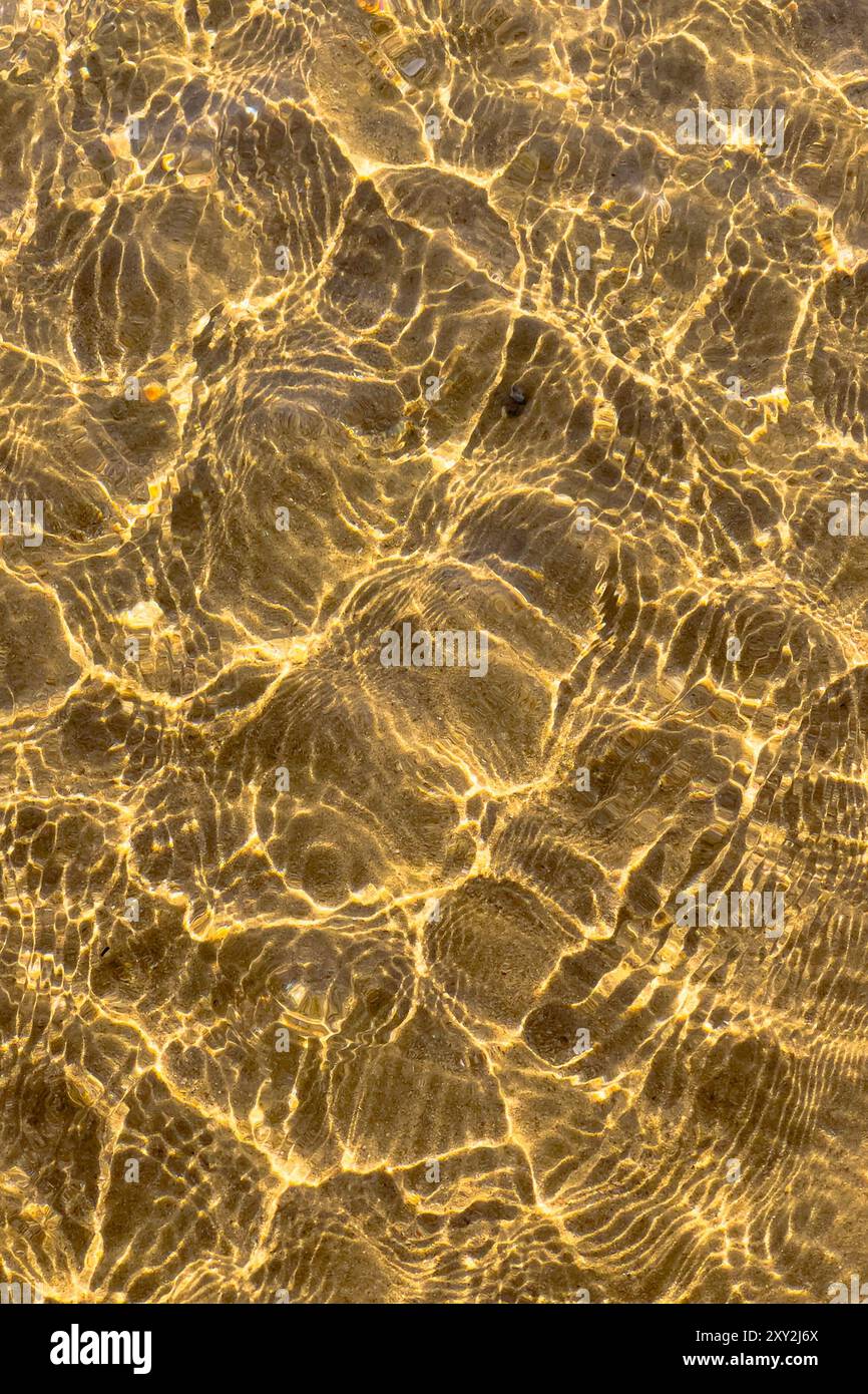 Golden ripples in shallow water creating intricate patterns Stock Photo ...