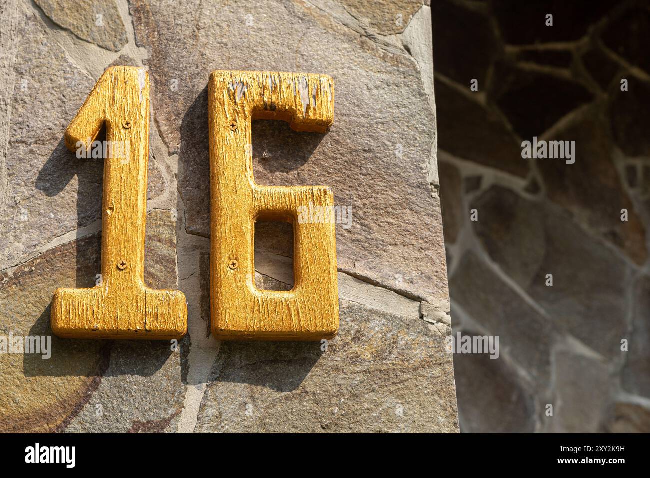 Yellow number sixteen on a stone wall Stock Photo - Alamy