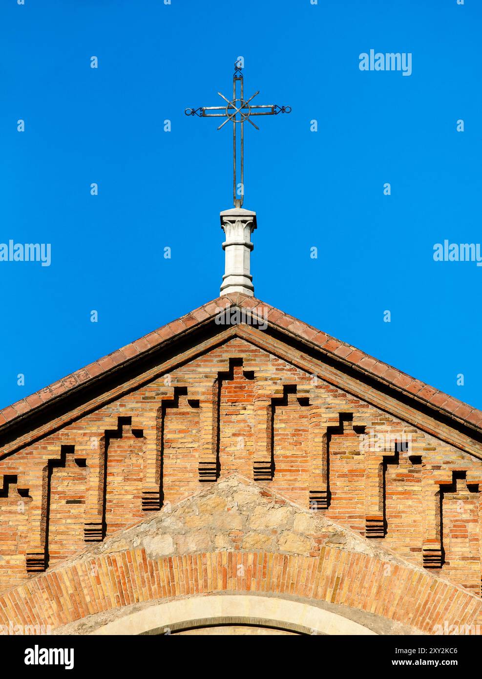 Gable of an old chapel with a cross on the top of the roof over clear ...