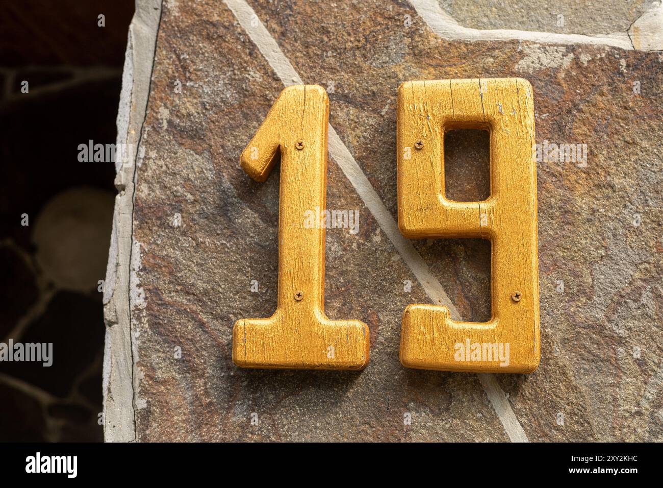 Yellow number nineteen on a stone wall Stock Photo - Alamy