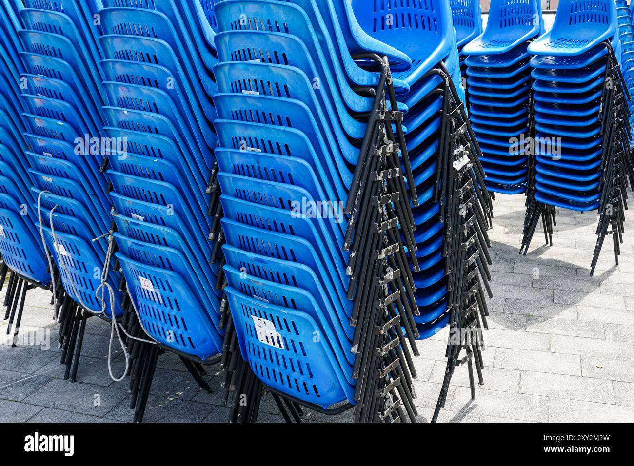 Stacked rows of blue plastic chairs with metal frames for outdoor ...