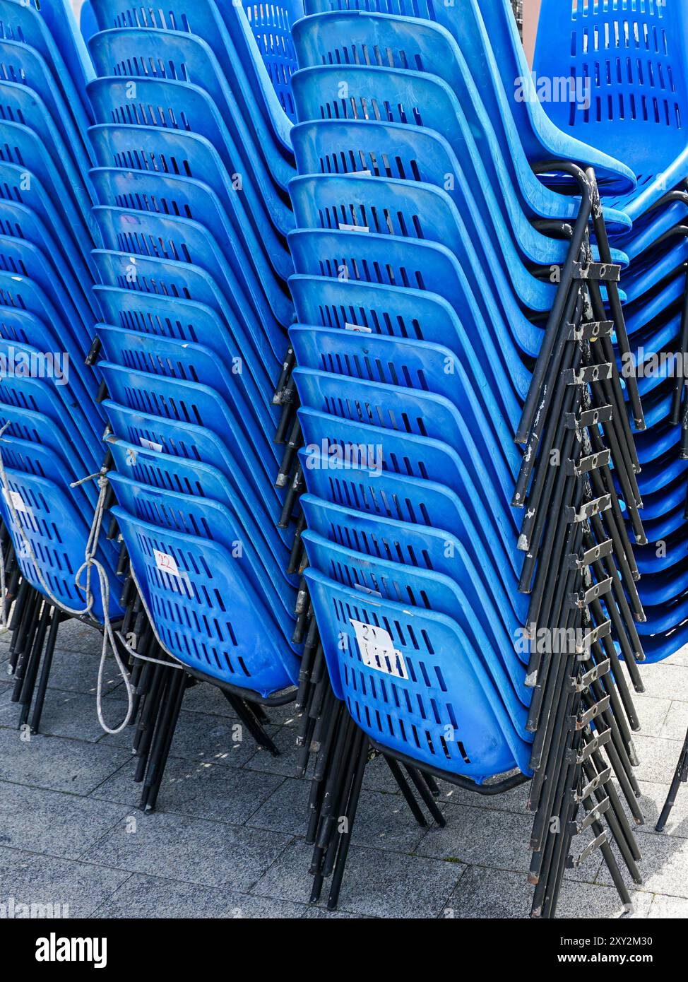 Stacked rows of blue plastic chairs with metal frames for outdoor ...