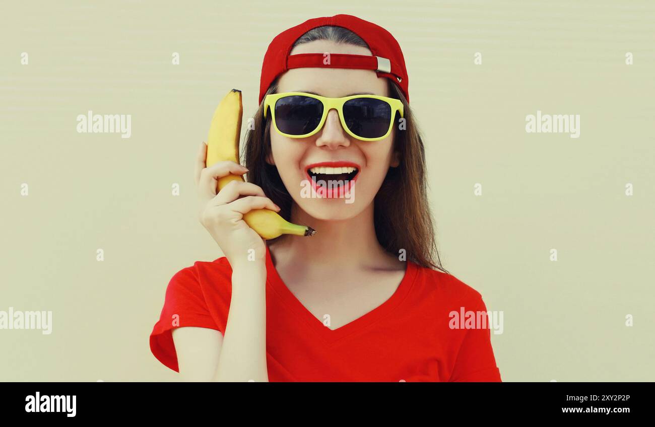 Portrait of funny woman calling on a banana phone on a white background ...