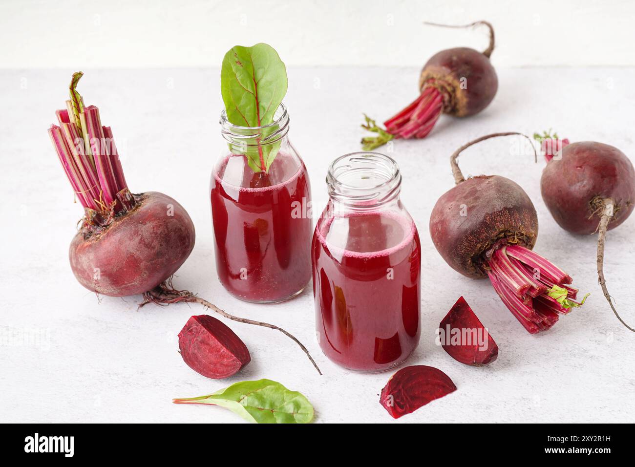 Bottles of fresh beetroot juice and vegetables on light background ...