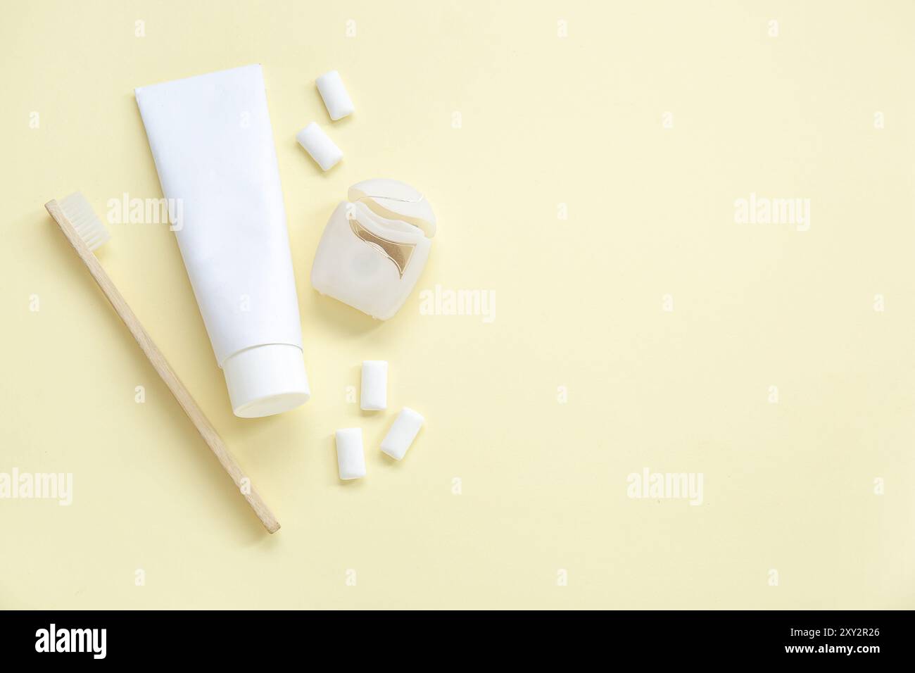 Toothpaste with brush, dental floss and chewing gums on light yellow ...