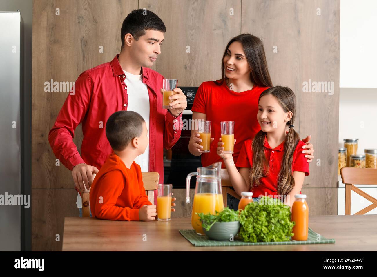 Happy parents with their little children drinking orange juice in ...
