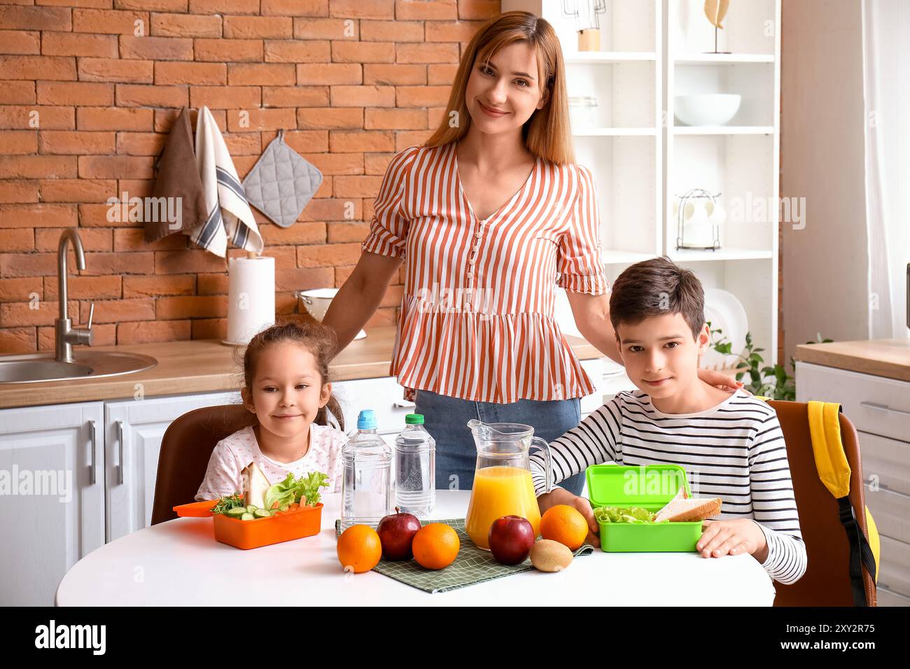 Little children with school lunch and their mother in kitchen Stock ...
