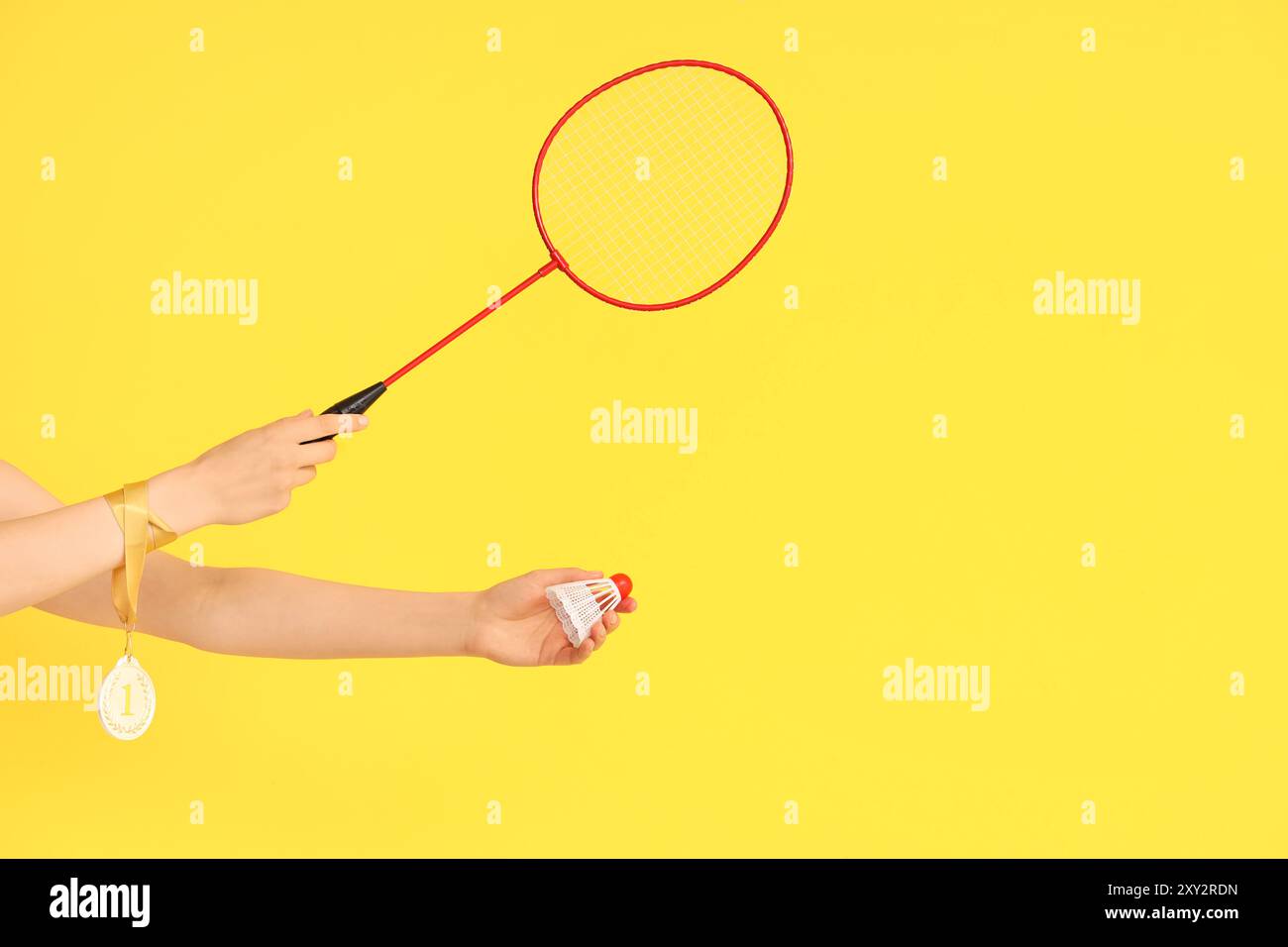 Female hands with badminton racket, shuttlecock and medal on yellow ...