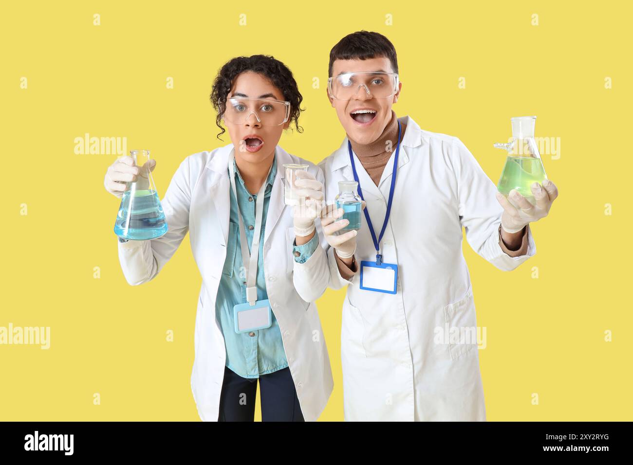 Shocked young chemists with flasks on yellow background Stock Photo - Alamy