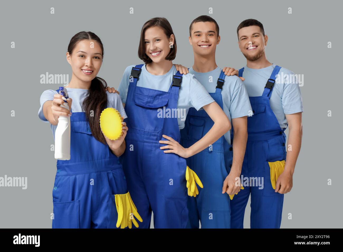 Group of young janitors with cleaning supplies on grey background Stock ...