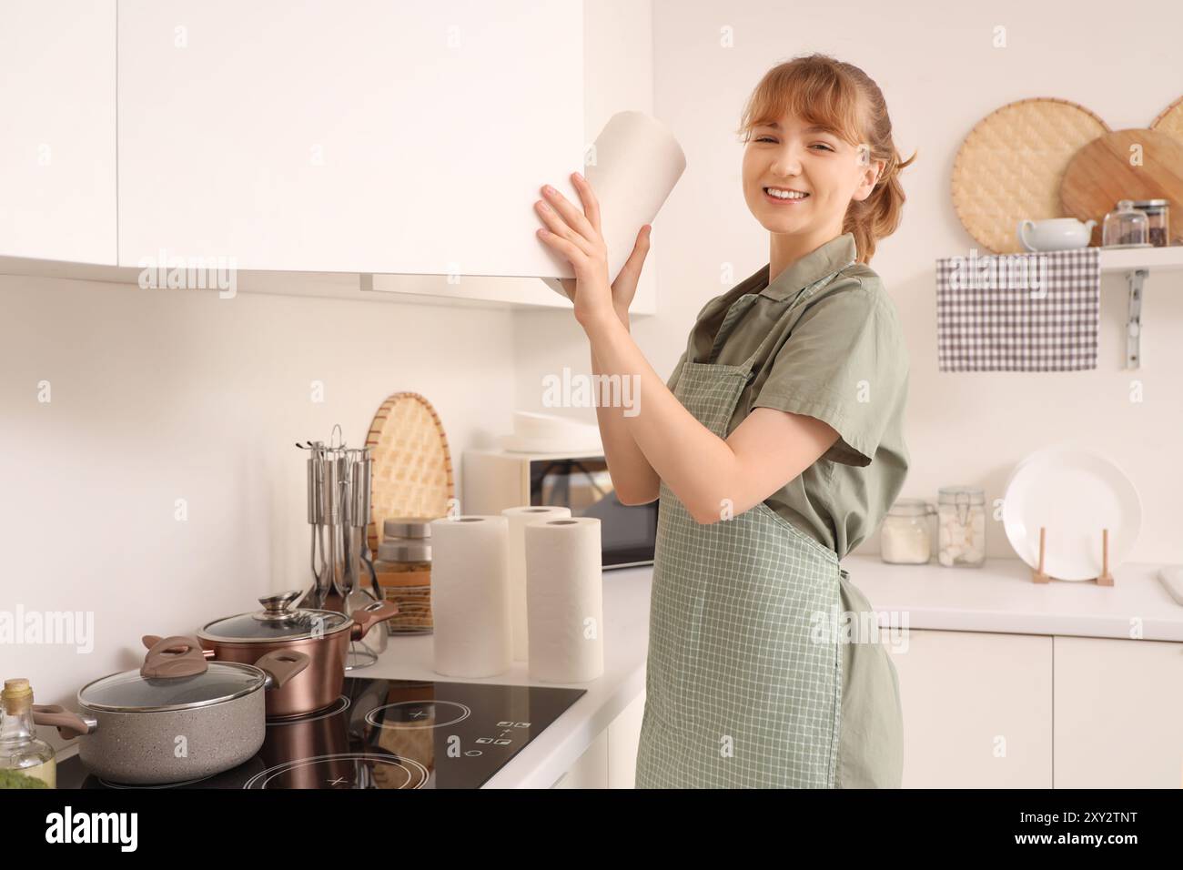 Young woman putting roll of paper towels in cupboard in kitchen Stock ...