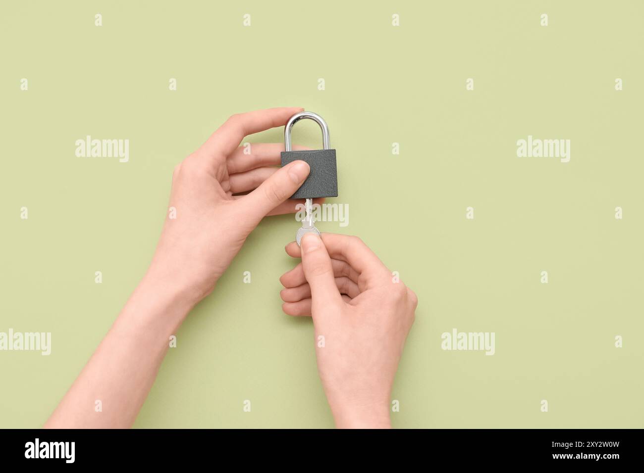 Hands with padlock and key on green background Stock Photo - Alamy